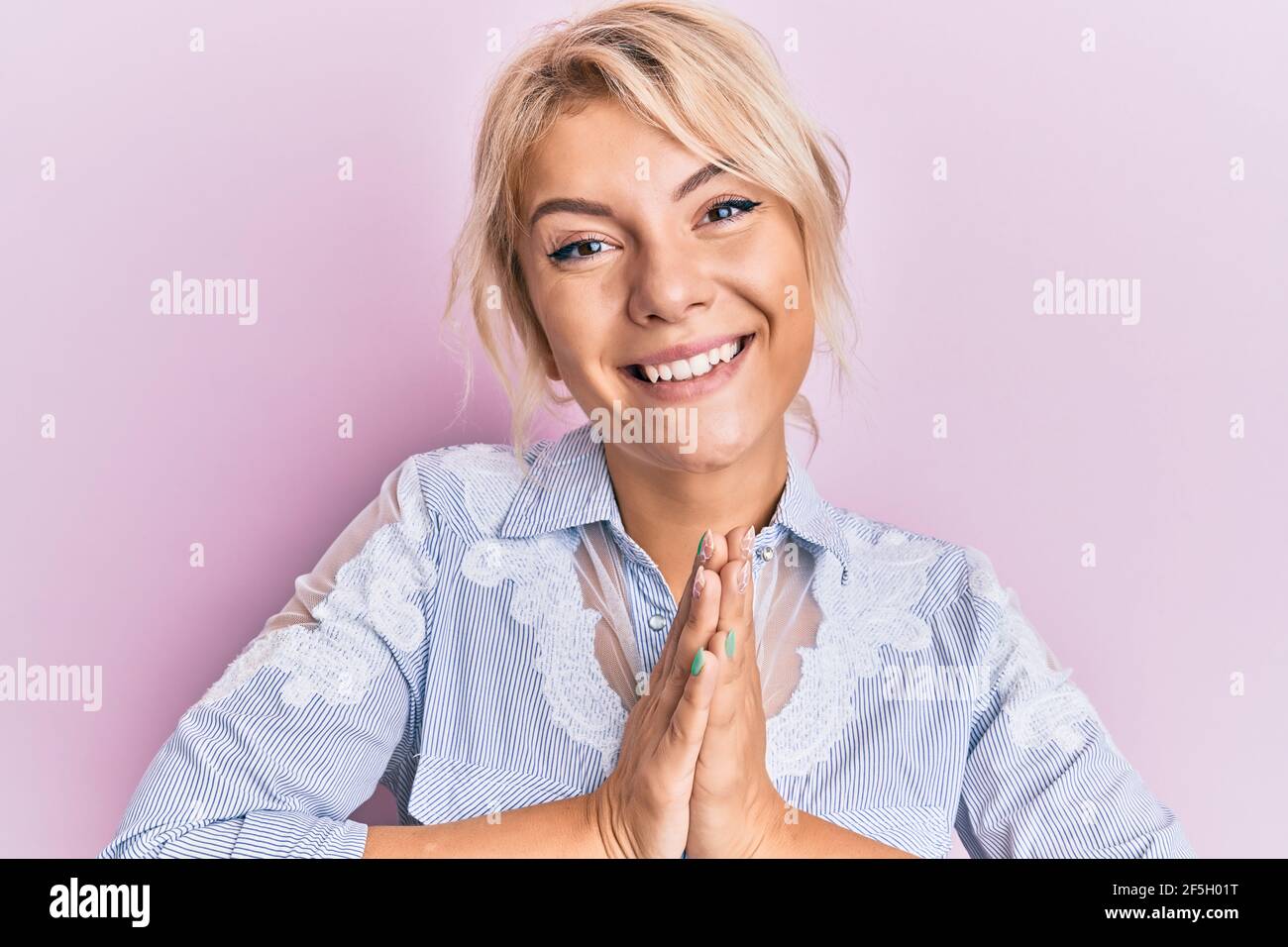 Young blonde girl wearing casual clothes praying with hands together ...