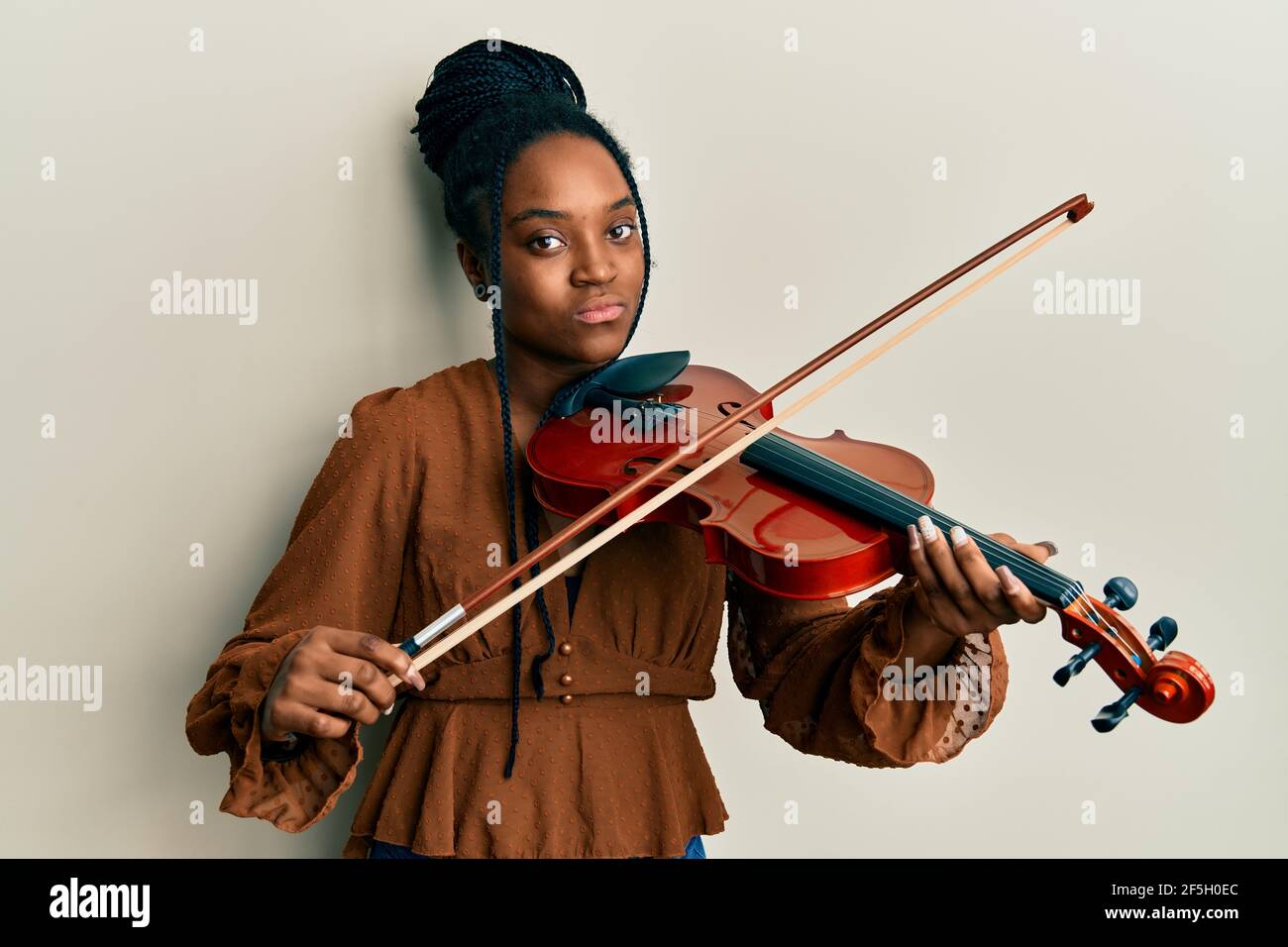 African american woman with braided hair playing violin depressed and ...