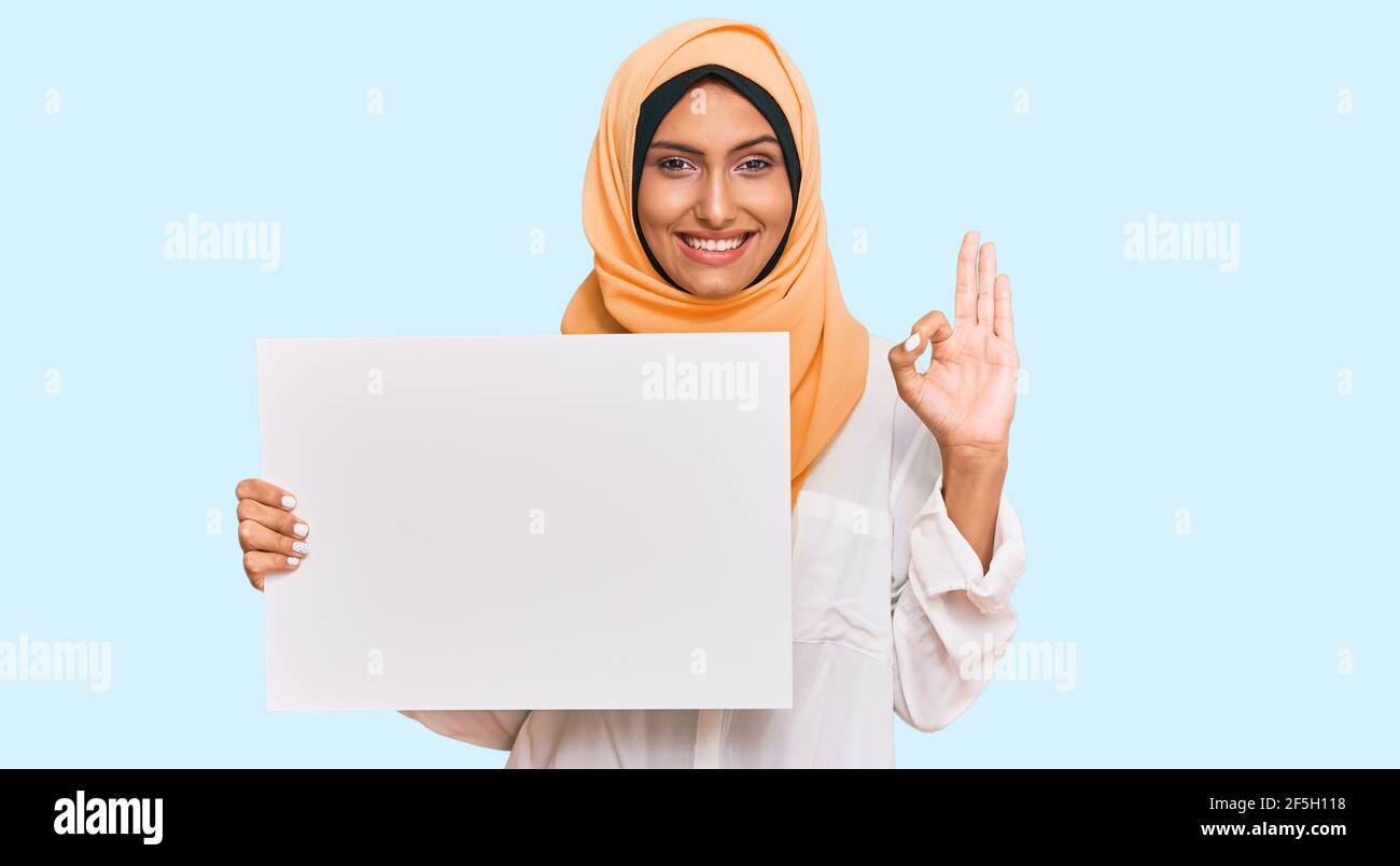 Young brunette arab woman wearing traditional islamic hijab holding ...