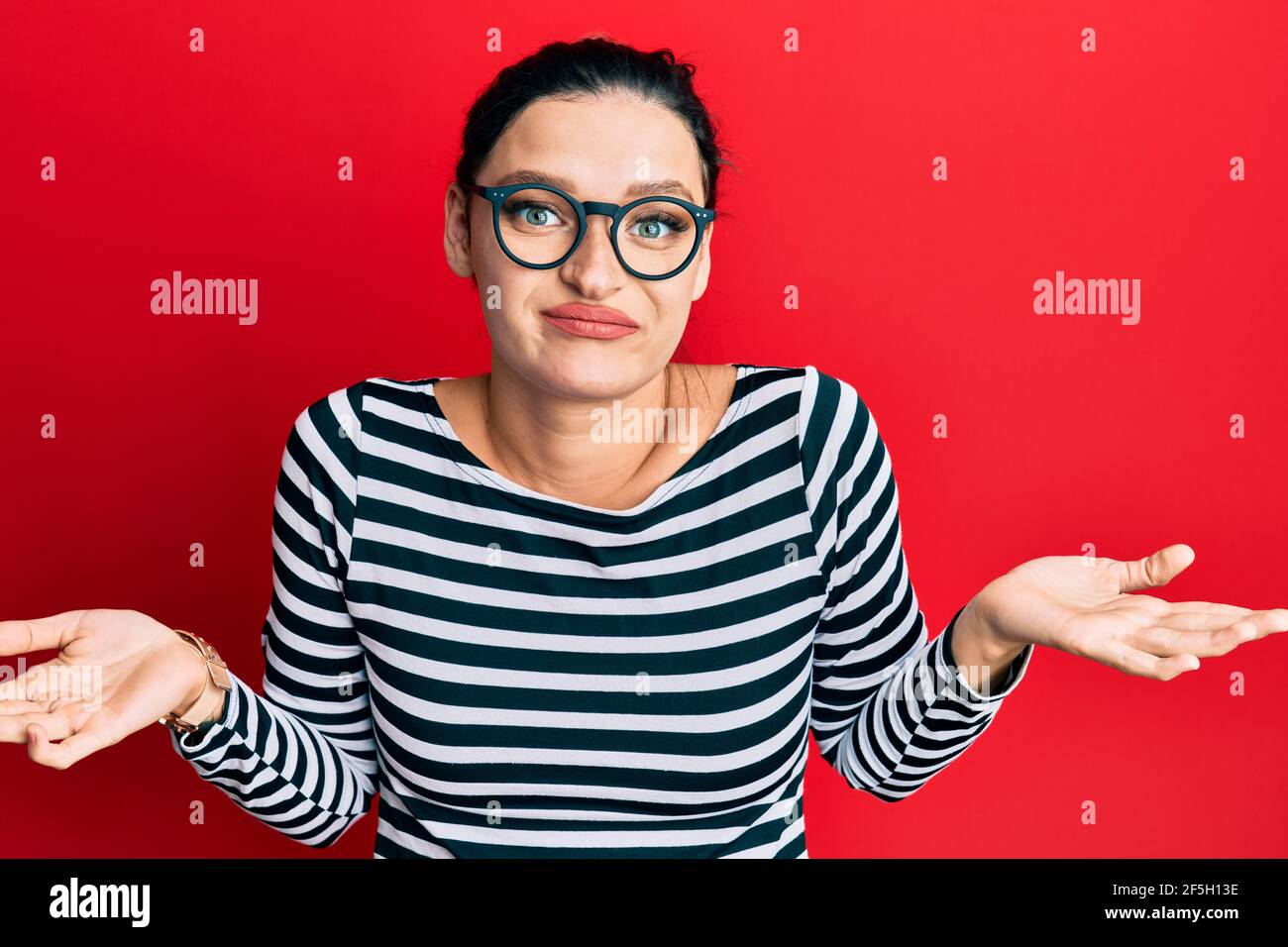 Young caucasian woman wearing casual clothes and glasses clueless and ...