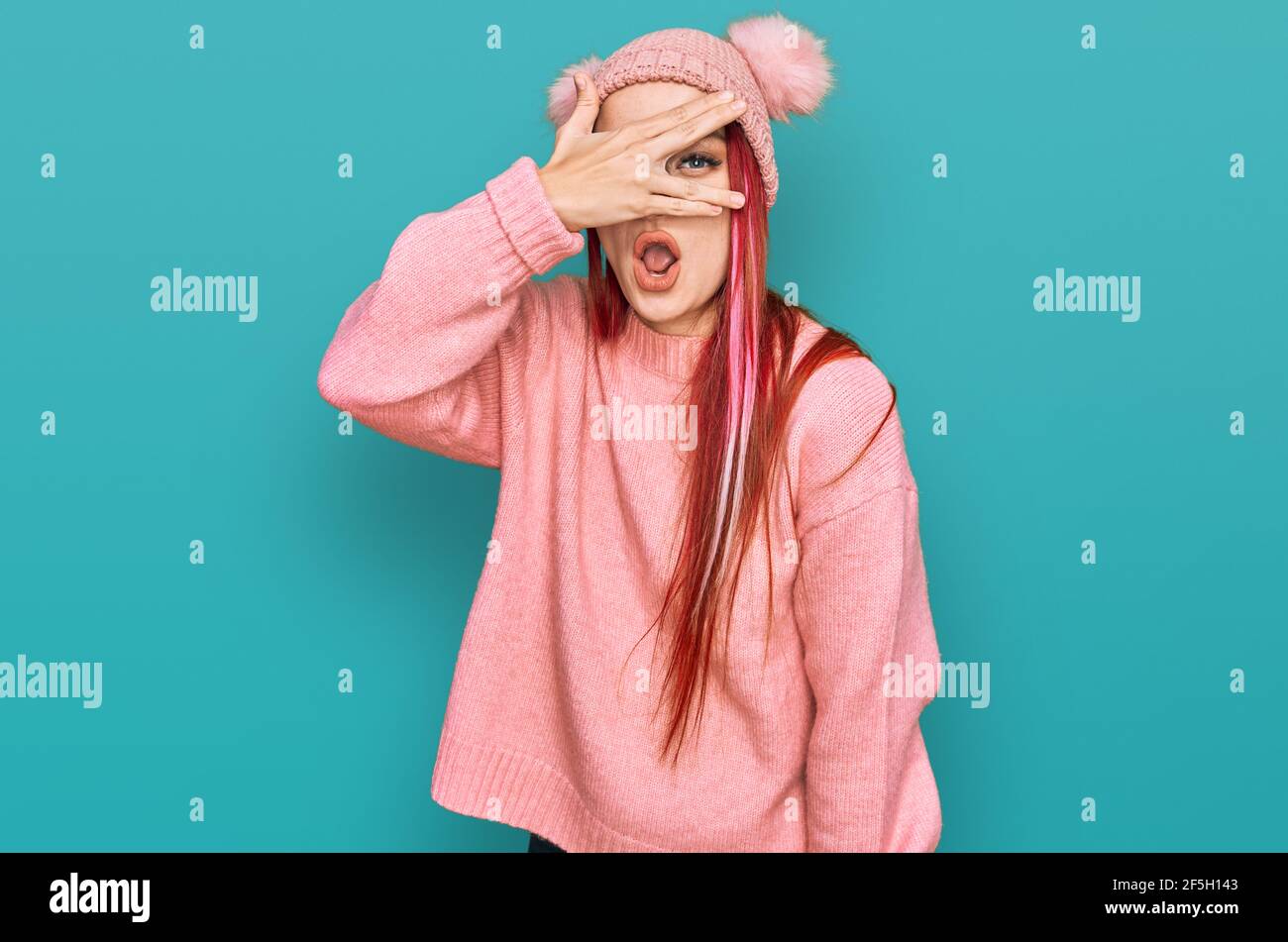 Young caucasian woman wearing casual clothes and wool cap peeking in ...
