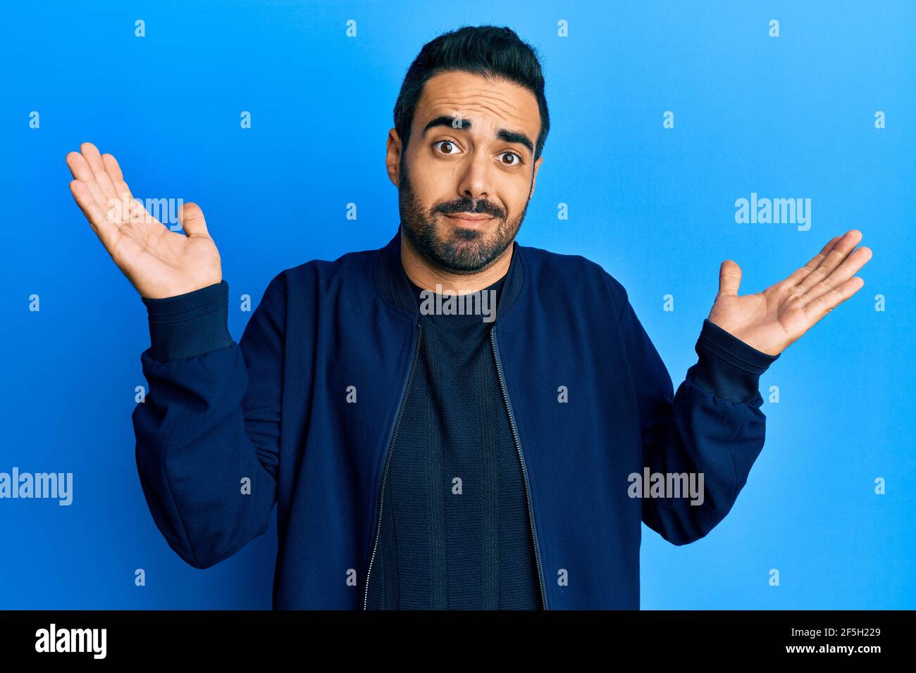 Young hispanic man wearing casual clothes clueless and confused with ...