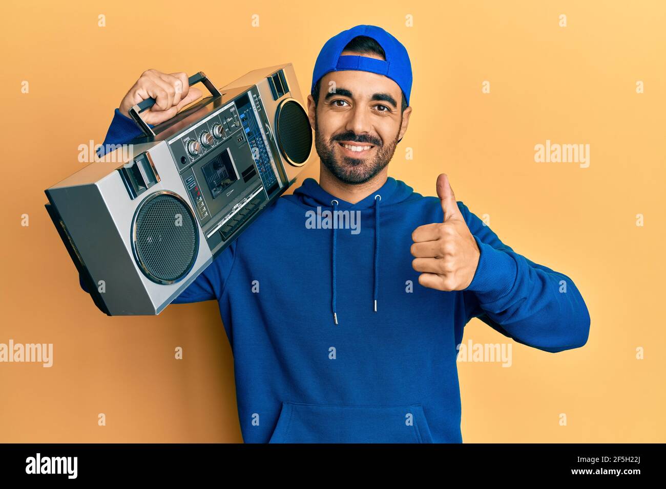 Young hispanic man holding boombox, listening to music smiling happy ...
