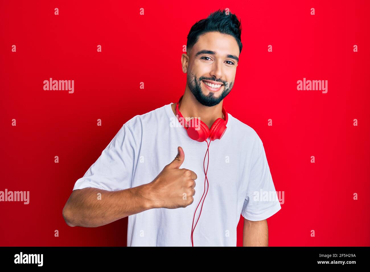 Young man with beard listening to music using headphones doing happy ...