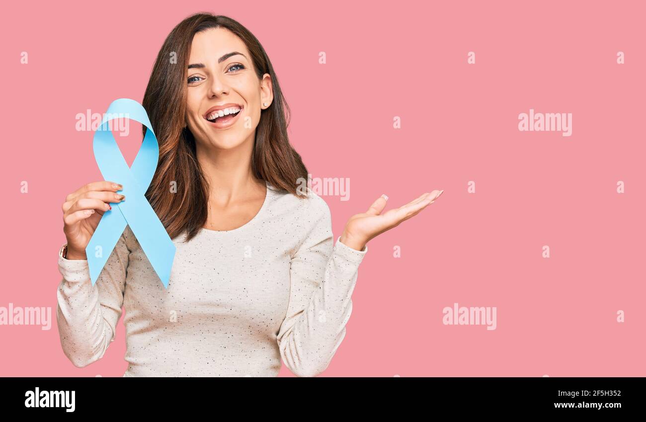 Young brunette woman holding blue ribbon celebrating victory with happy ...