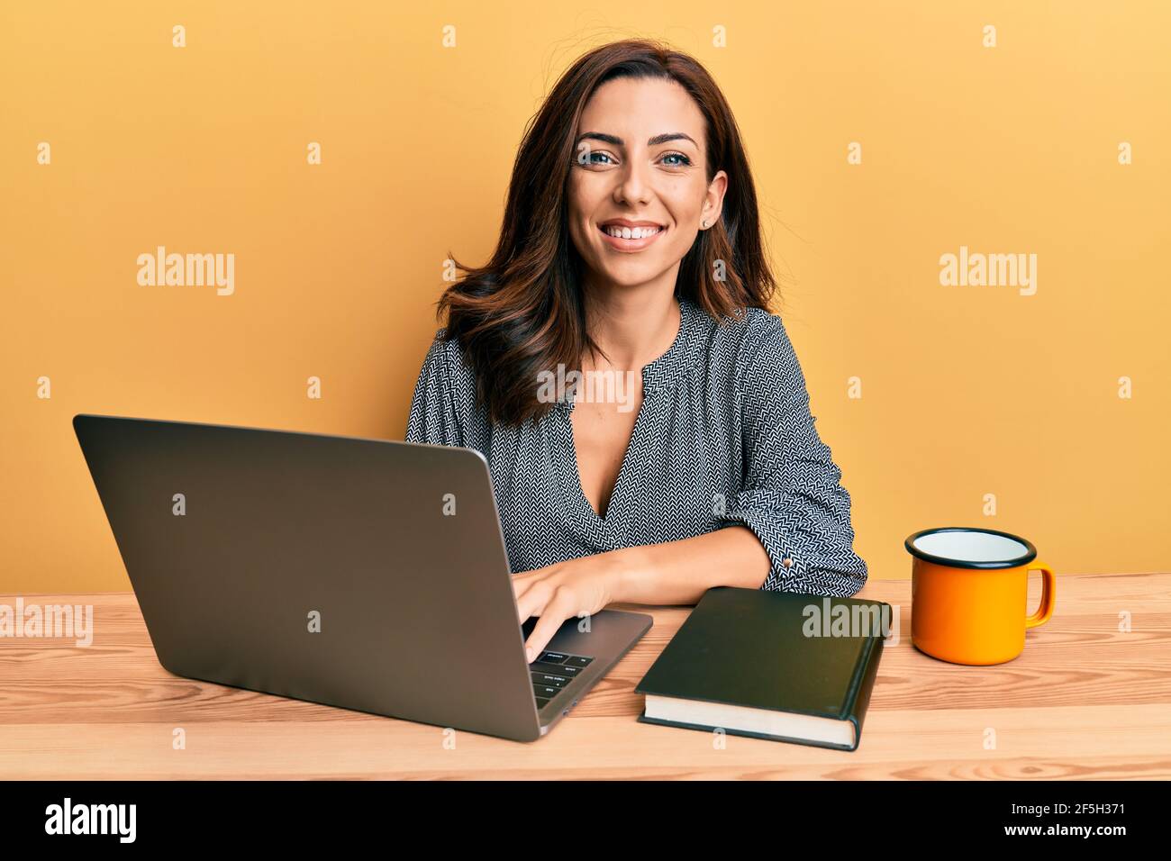 Young brunette woman working using computer laptop looking positive and ...