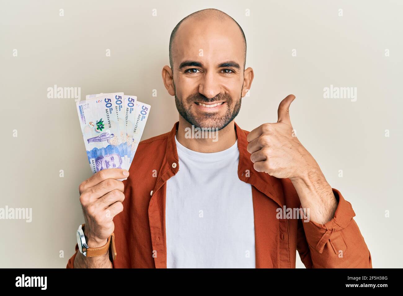 Young hispanic business man holding 50 mexican pesos banknotes smiling ...