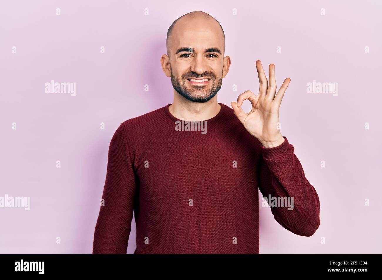 Young bald man wearing casual clothes smiling positive doing ok sign ...