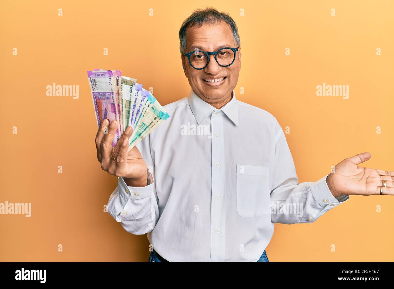 Middle age indian man holding indian rupee banknotes celebrating ...