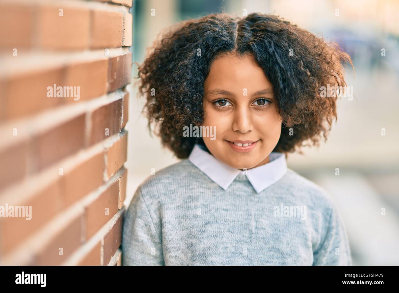 Adorable hispanic student child girl smiling happy standing at the city ...