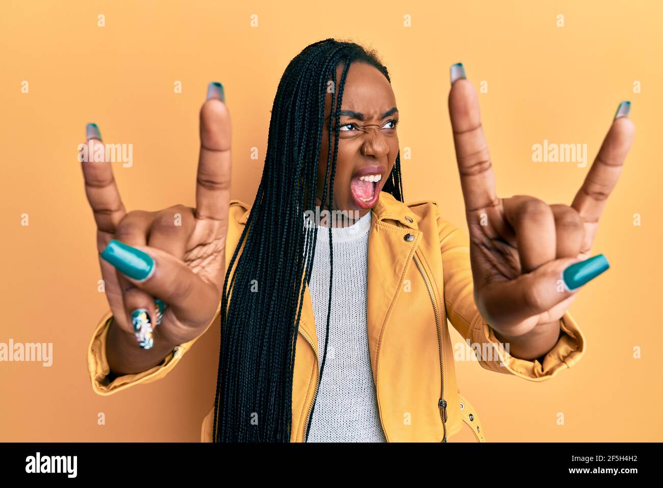 Young african american woman doing rock gesture angry and mad screaming ...