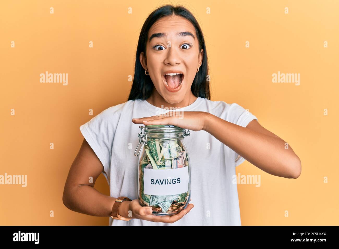 Young asian woman holding jar with savings celebrating crazy and amazed ...
