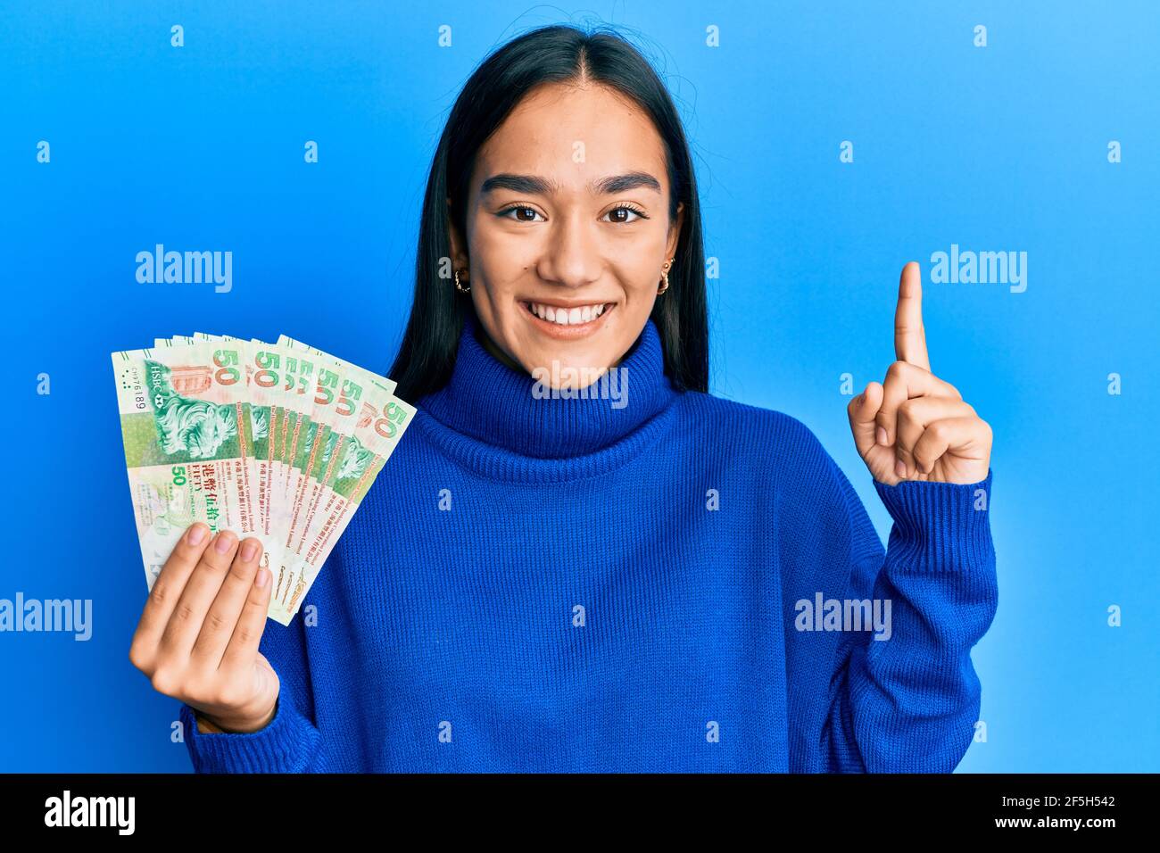 Young asian woman holding 50 hong kong dollars banknotes smiling with ...