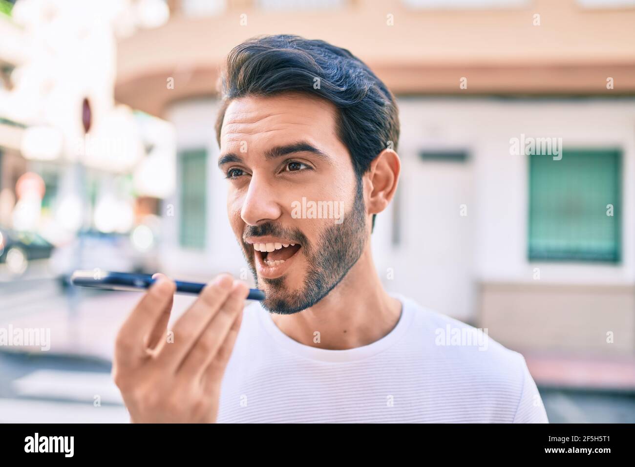 Young hispanic man smiling happy sending audio message using smartphone ... Young hispanic man smiling happy sending audio message using smartphone ...