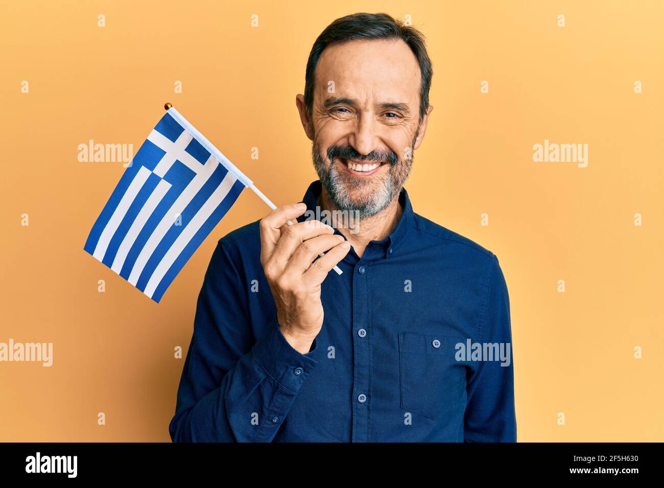 Middle age hispanic man holding greece flag looking positive and happy ...