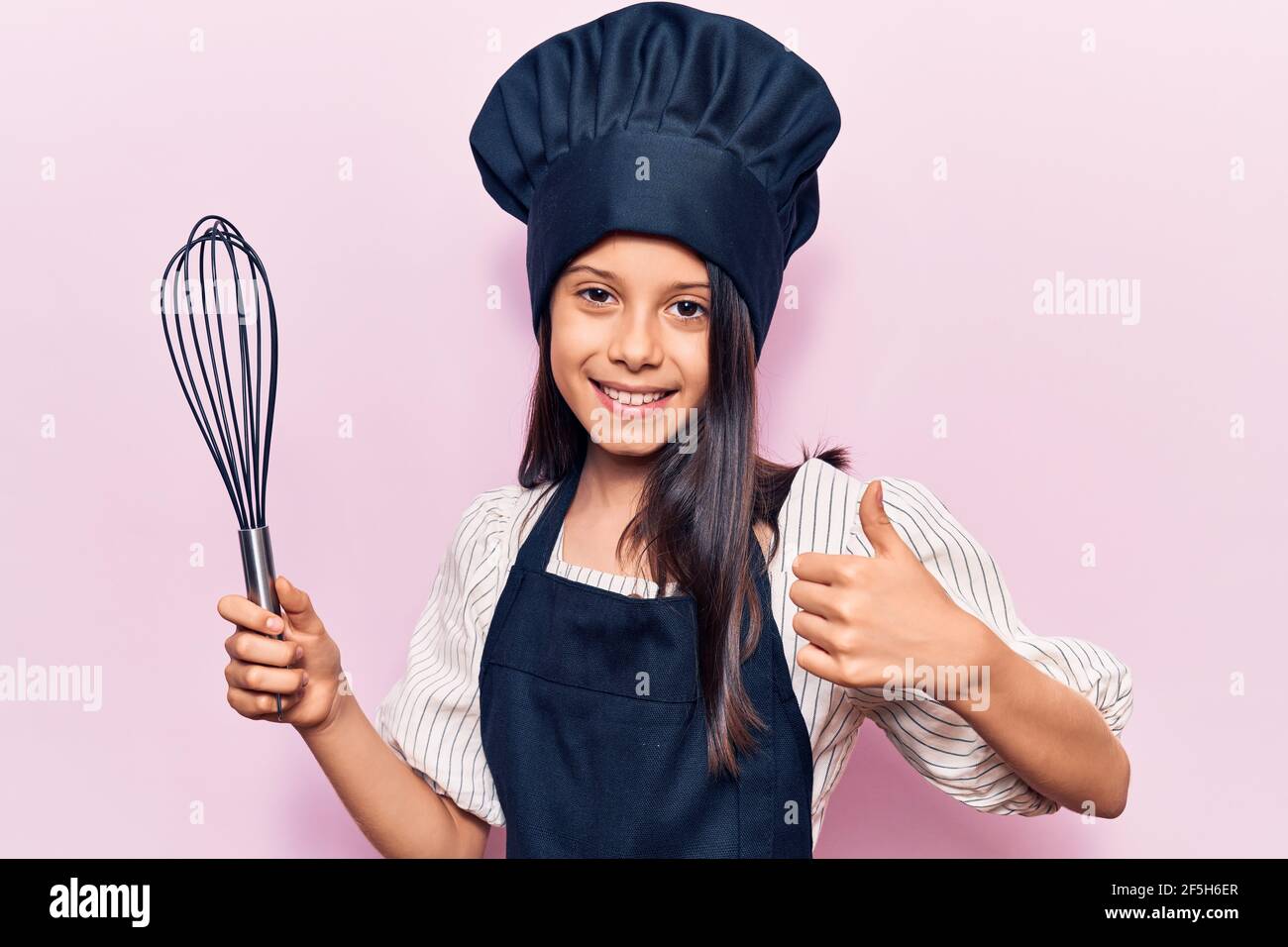 Beautiful child girl wearing cooker uniform holding whisk smiling happy ...