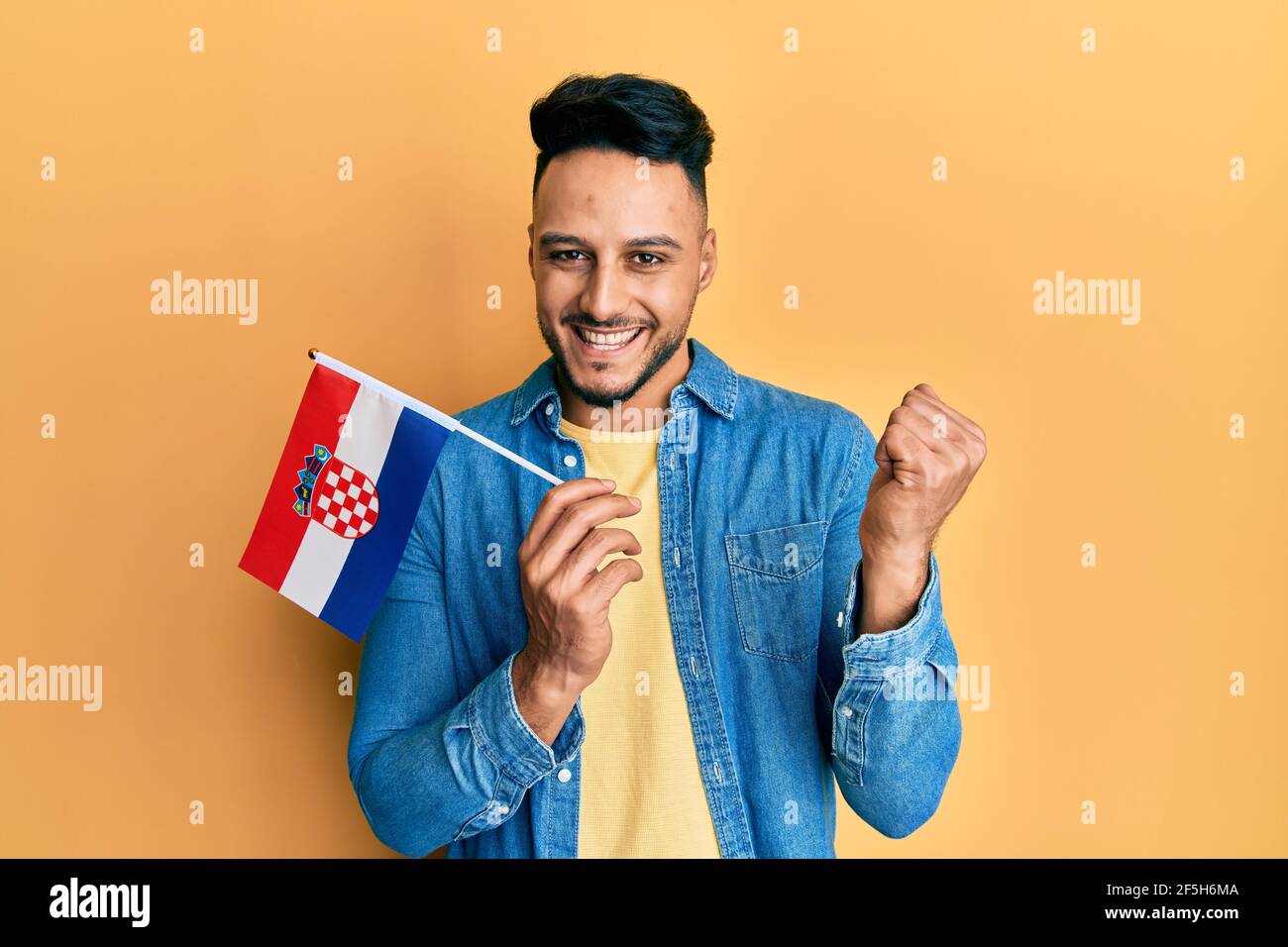 Young arab man holding croatia flag screaming proud, celebrating ...