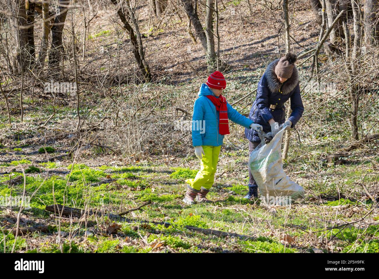 A girl and a woman collect garbage at the forest edge Stock Photo - Alamy