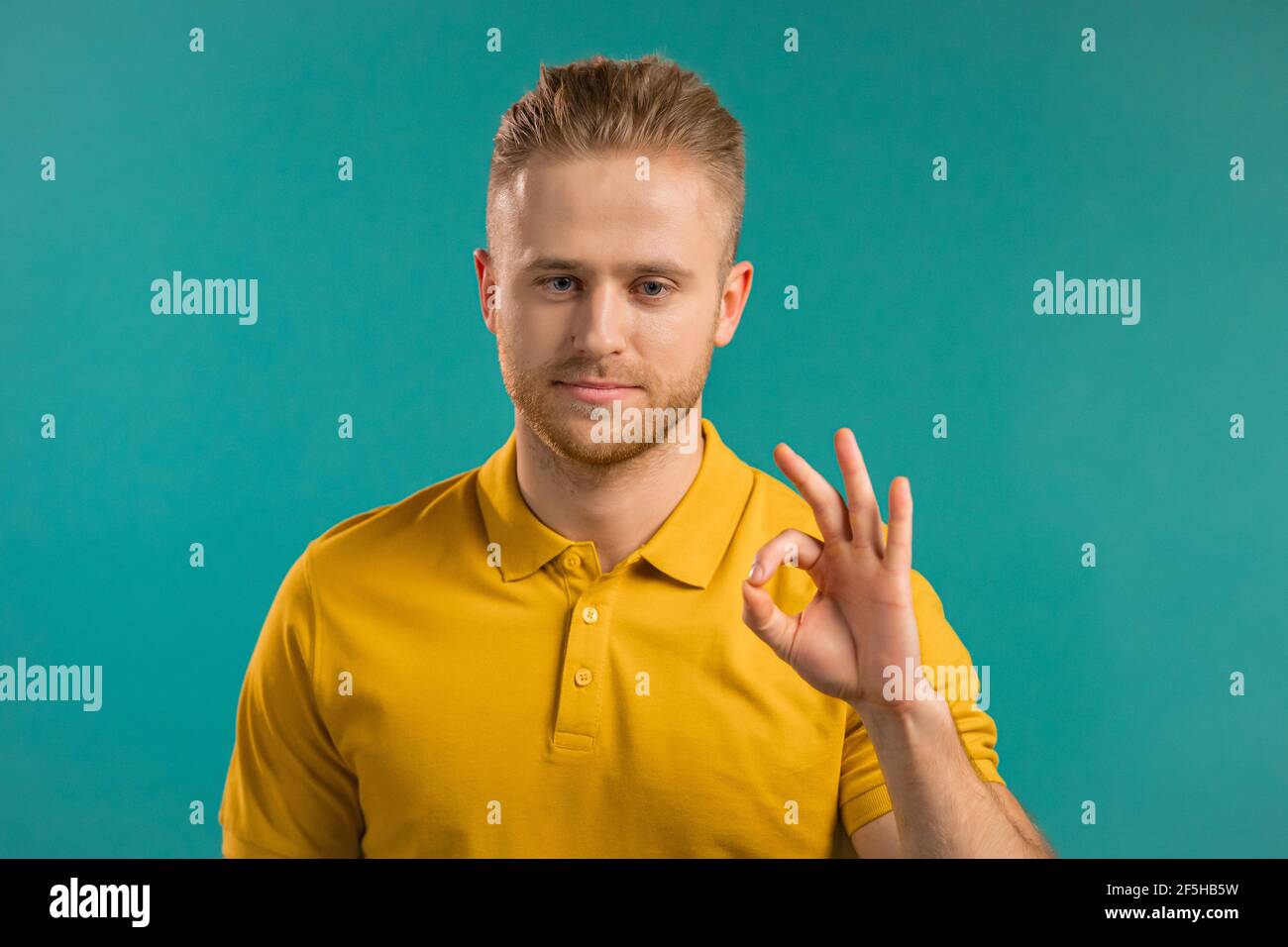 Handsome man shows okay, ok gesture. Happy guy on blue background ...