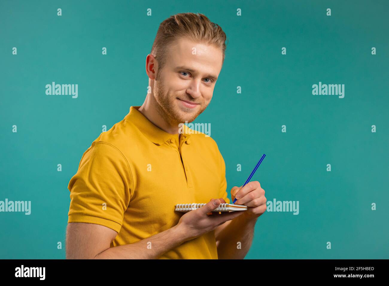 Handsome young man making notes in planner, guy holding pen, reflects ...