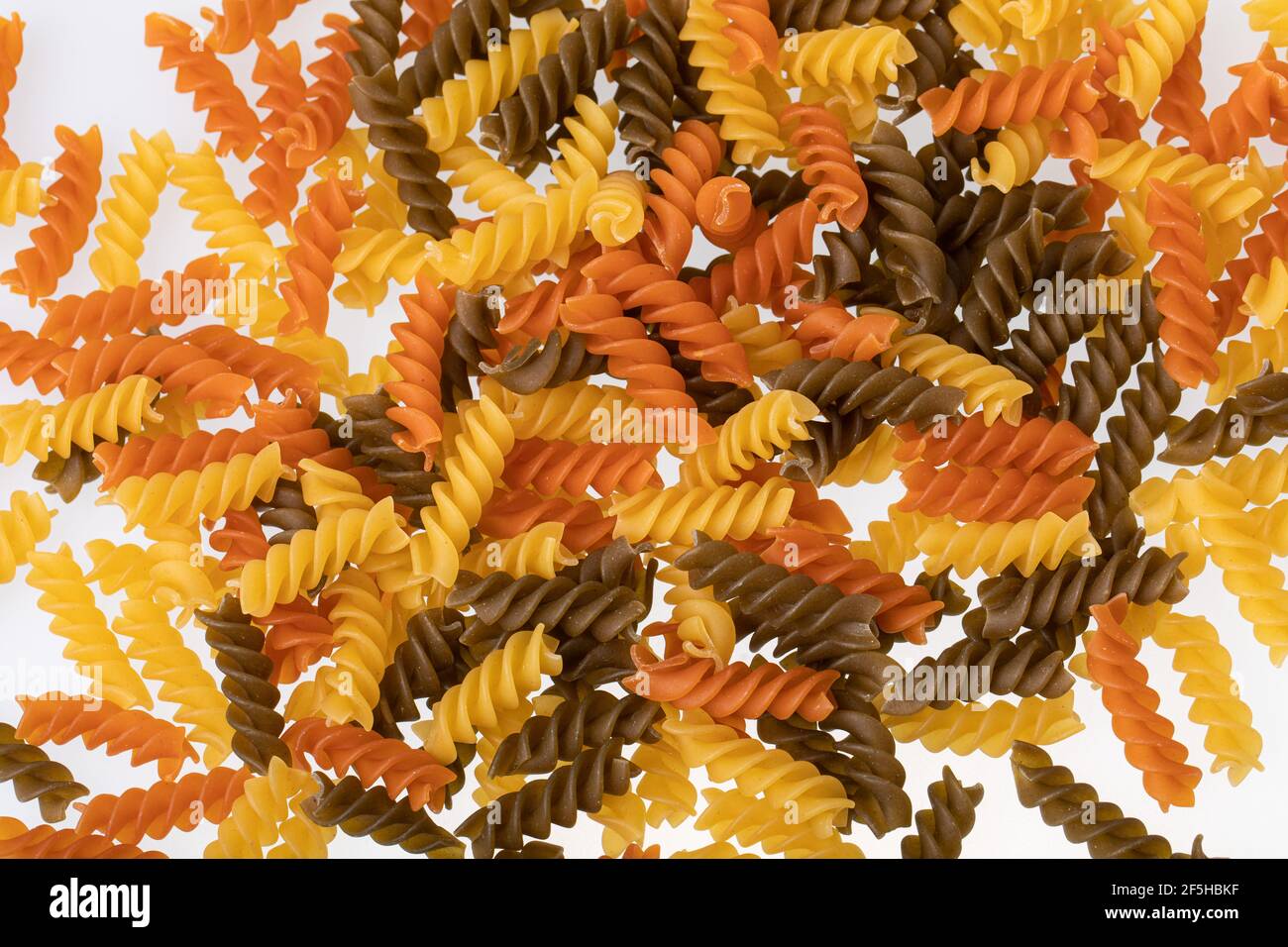Raw and uncooked colorful spiral pasta background on white Stock Photo ...