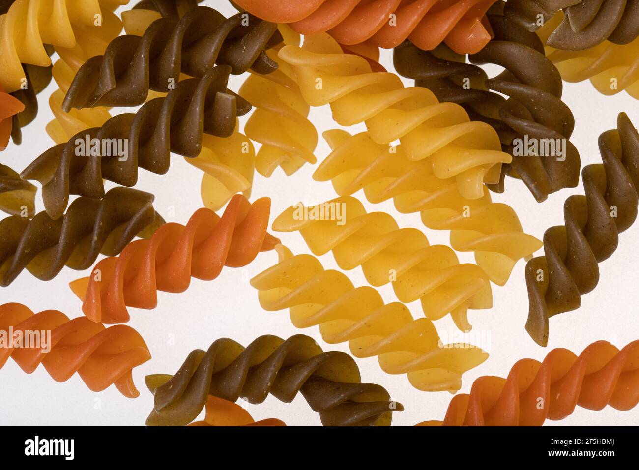 Raw and uncooked colorful spiral pasta background on white Stock Photo ...