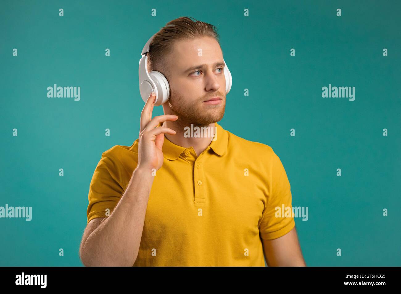 Handsome young man listening to music with wireless headphones, guy ...