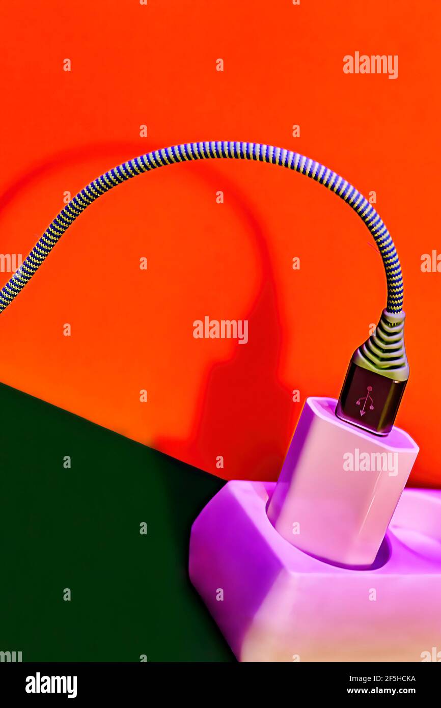 Charging cable inside on electric socket on colorful background Stock ...