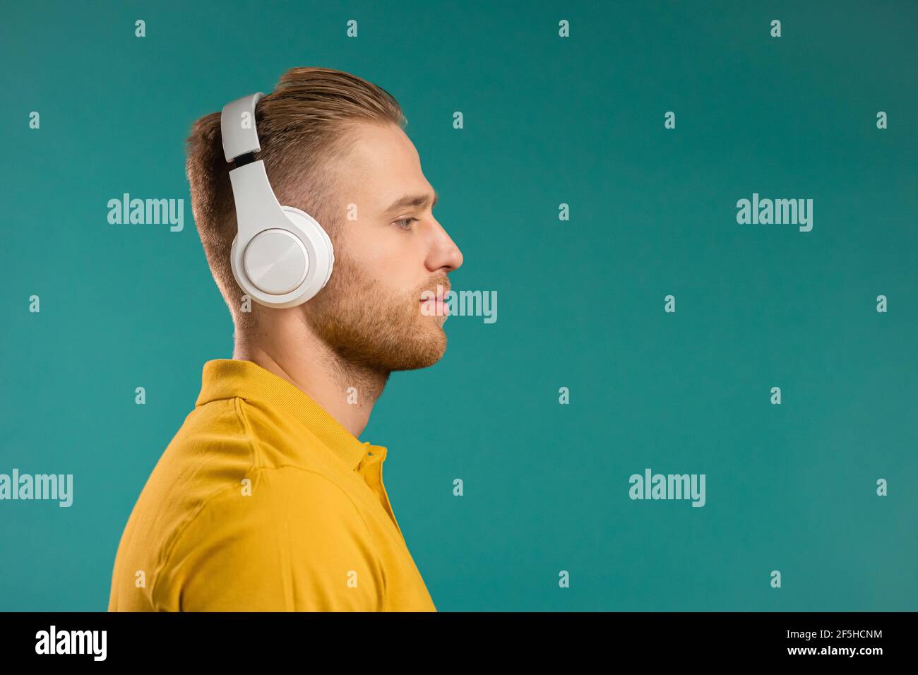 Handsome young man listening to music with wireless headphones, guy ...