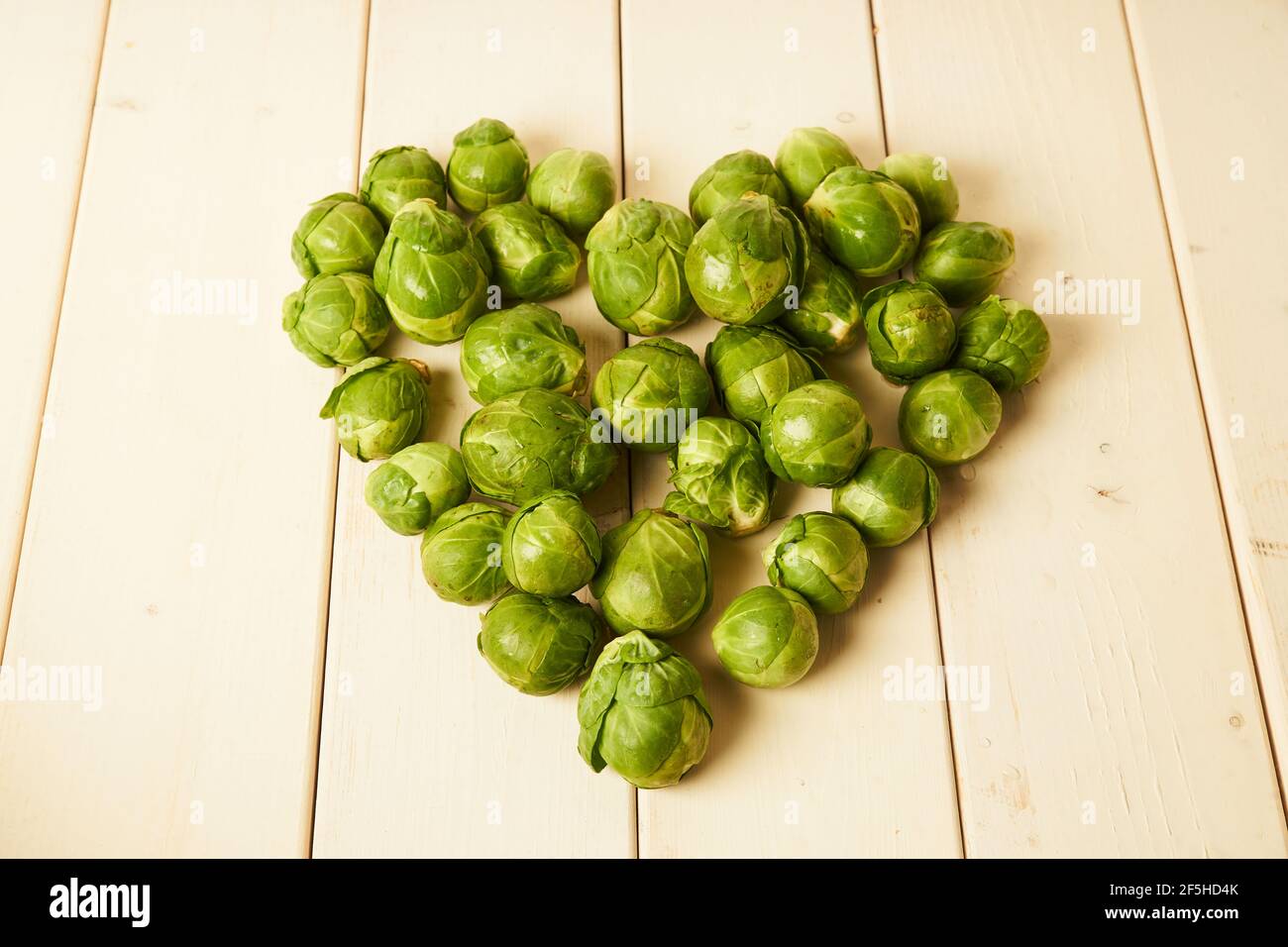 Bunch of fresh raw Brussel sprouts placed in heart shape on a white ...