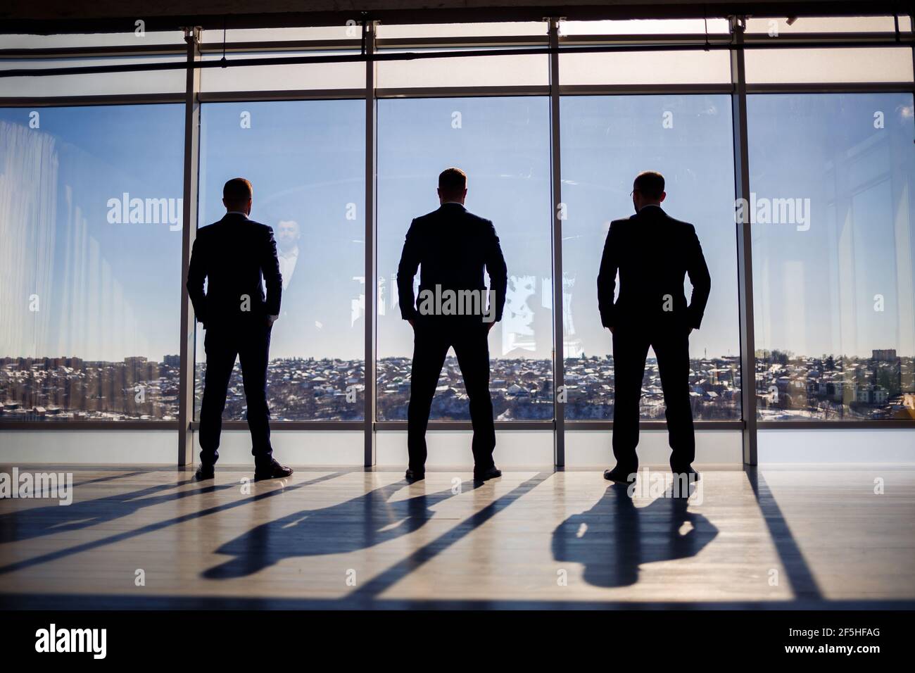 Dark male silhouettes against the background of a panoramic window ...