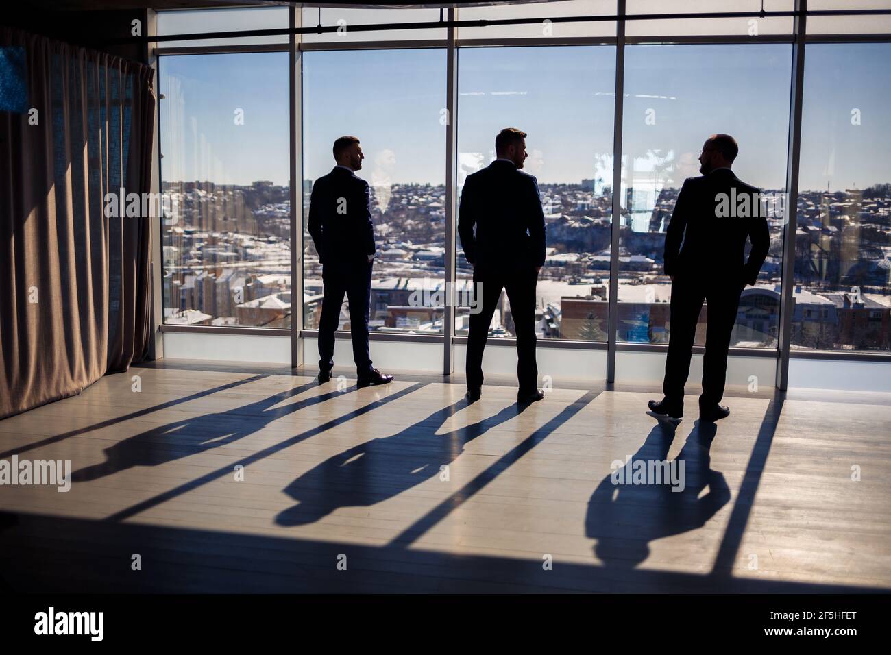 Dark male silhouettes against the background of a panoramic window ...