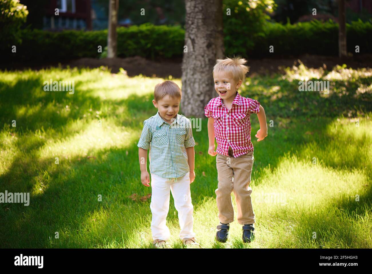 Two boys brothers playing and jumping outdoors in a park Stock Photo ...