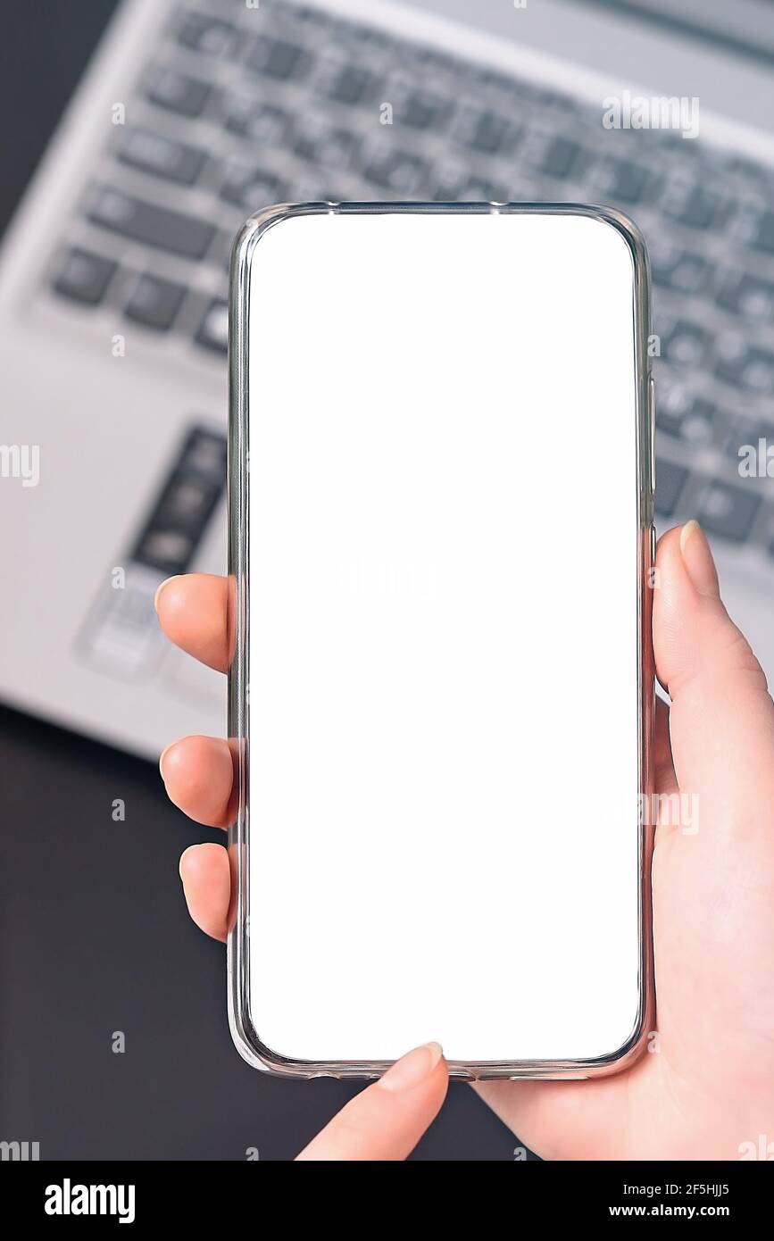 a woman holding phone showing white screen on top view, workplace home ...