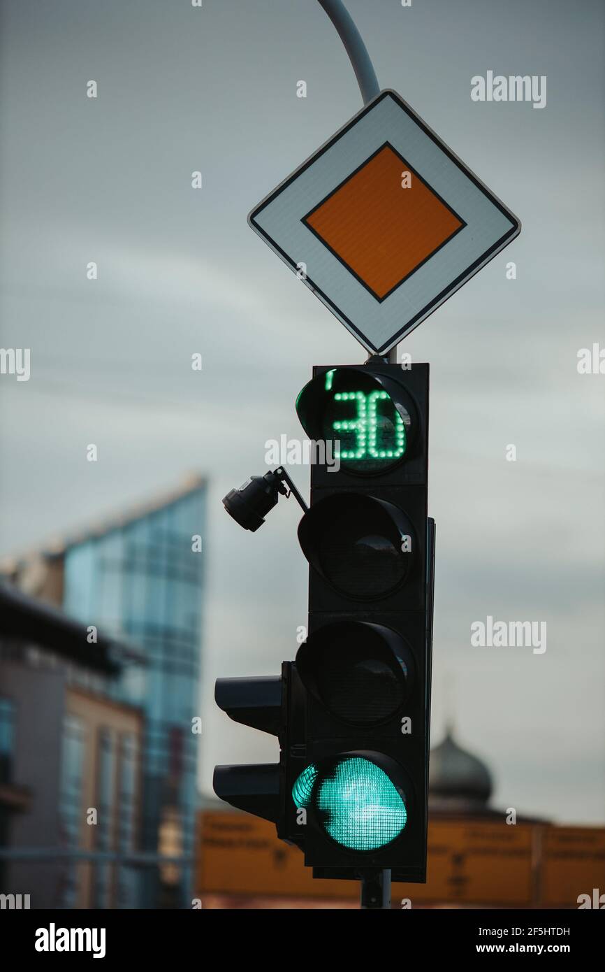 Closeup of a green traffic light for cars and the main road sign; 30 ...