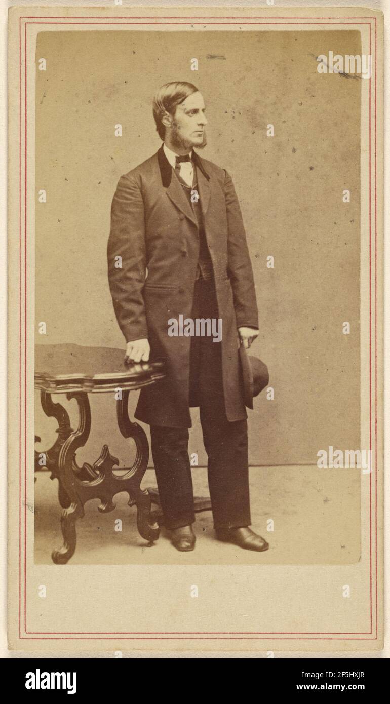 Unidentified man with long muttonchops standing, holding his hat in his ...