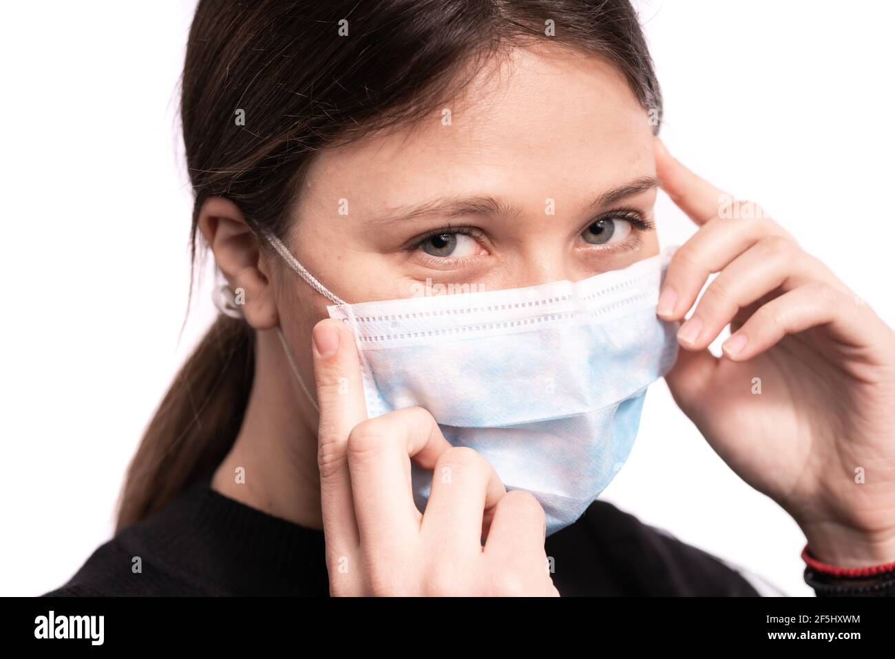 Beautiful young woman posing with mask, wearing black studio shot on ...