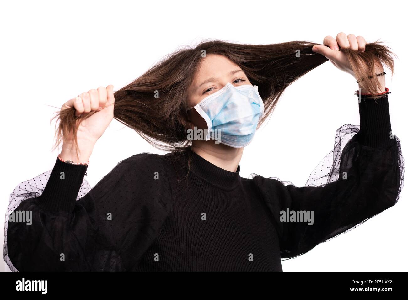 Beautiful young woman posing with mask, wearing black and pull hair ...