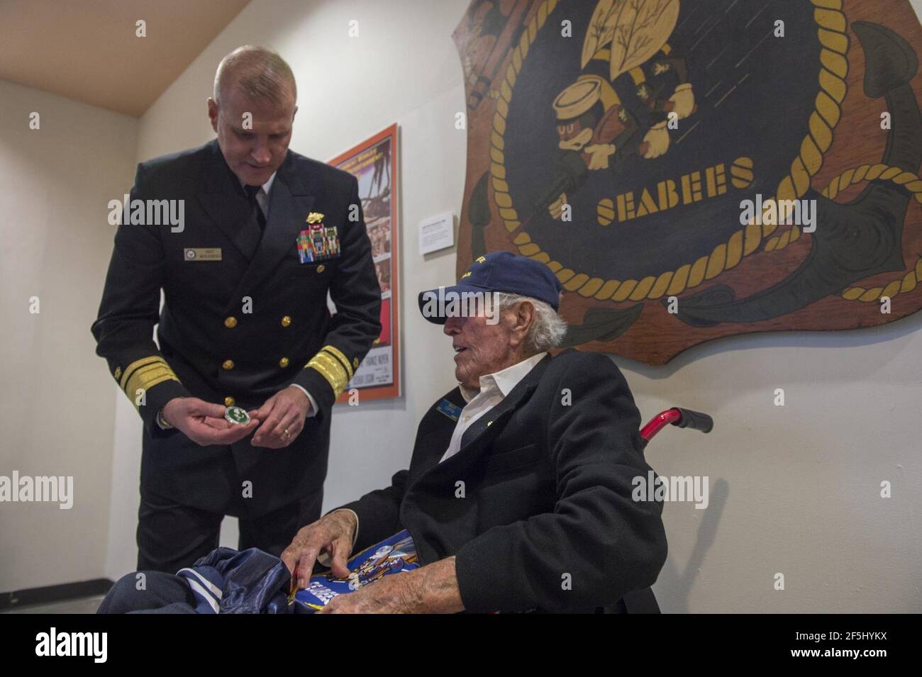 Rear Adm. Bret Muilenburg presents a coin to retired Carpenter’s Mate ...
