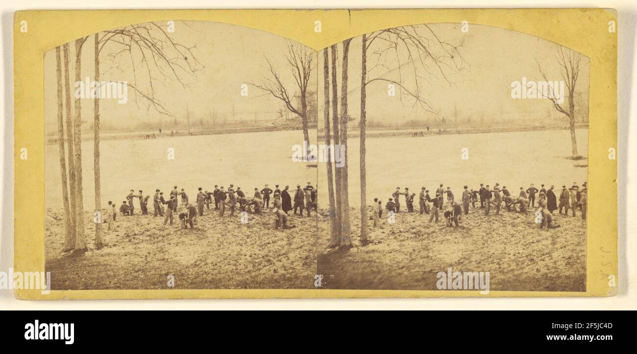 Large group of men at open field with barren trees, lake in background ...