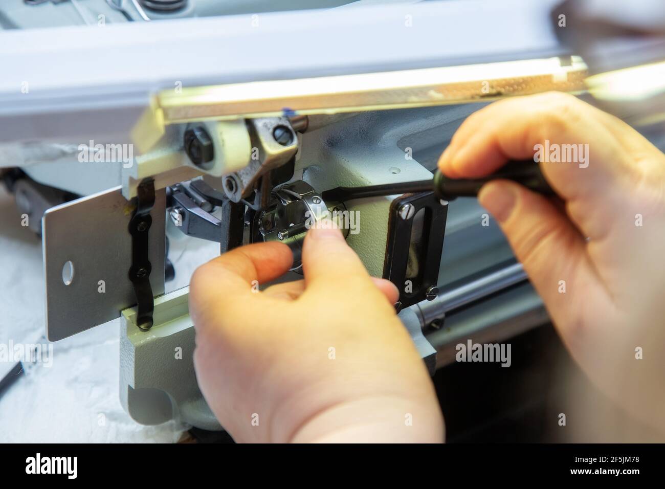 Female hands with a screwdriver repair the shuttle of the sewing ...