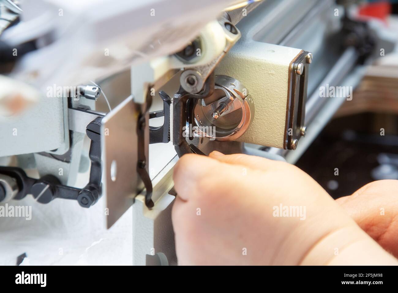 Female hands with a screwdriver repair the shuttle of the sewing ...