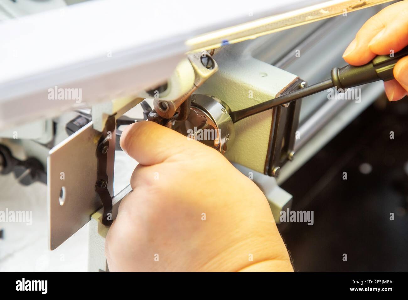 Female hands with a screwdriver repair the shuttle of the sewing ...
