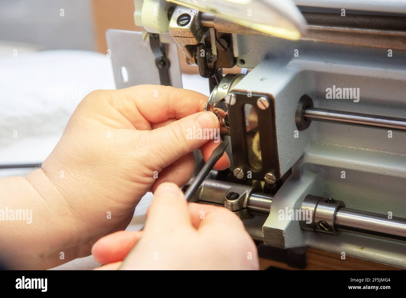 Female hands with a screwdriver repair the shuttle of the sewing ...