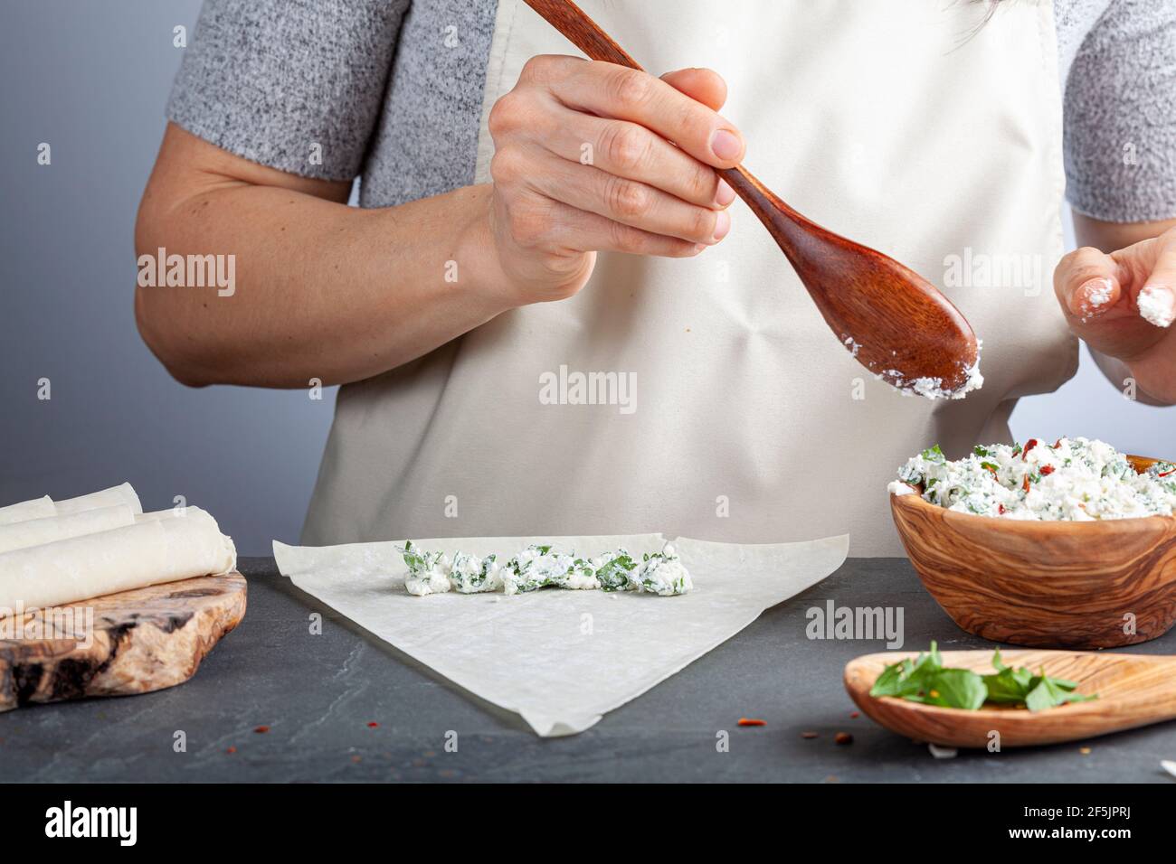 A caucasian woman is filling phyllo dough sheets known as yufka with ...