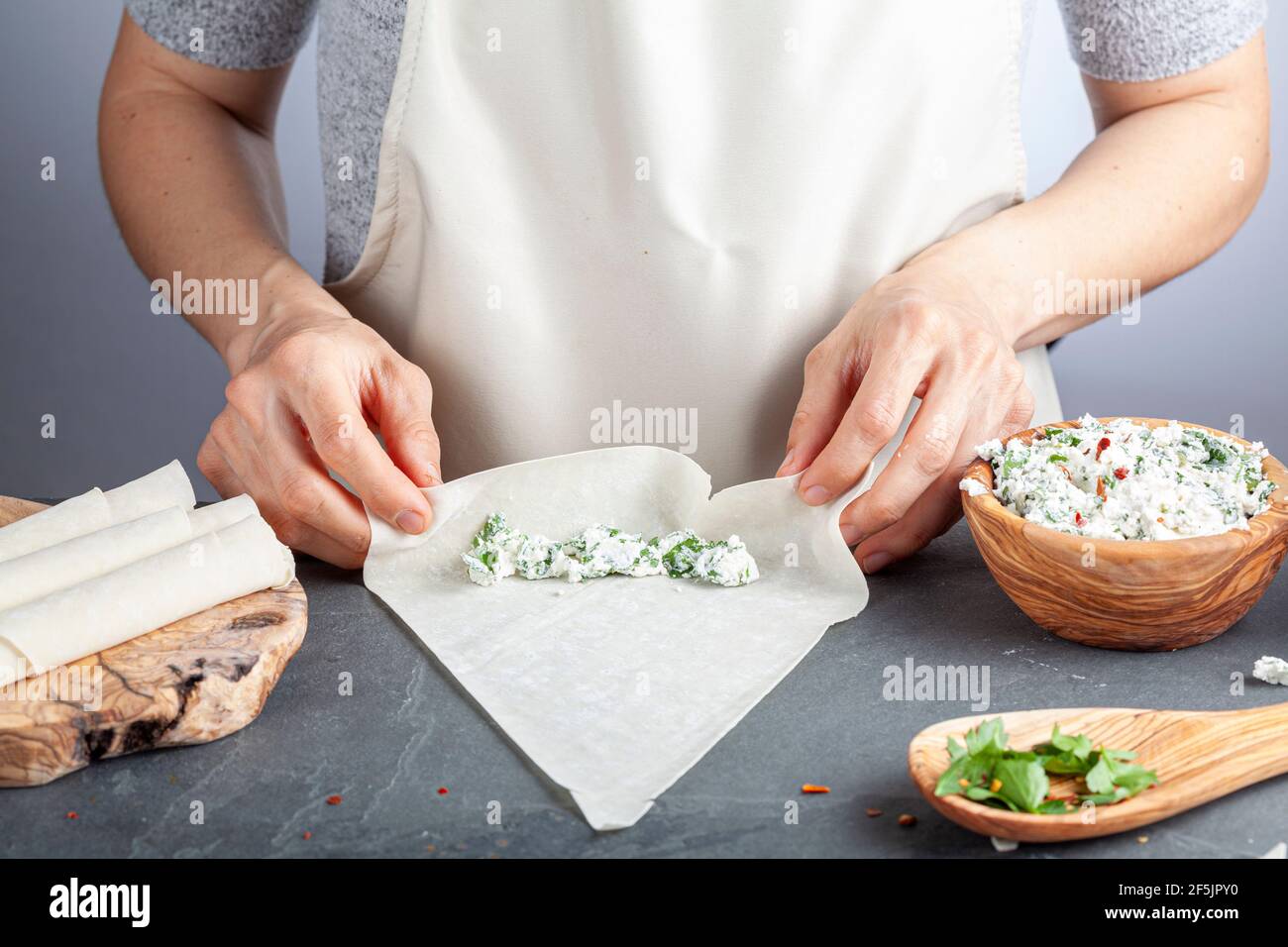A caucasian woman is filling phyllo dough sheets known as yufka with ...