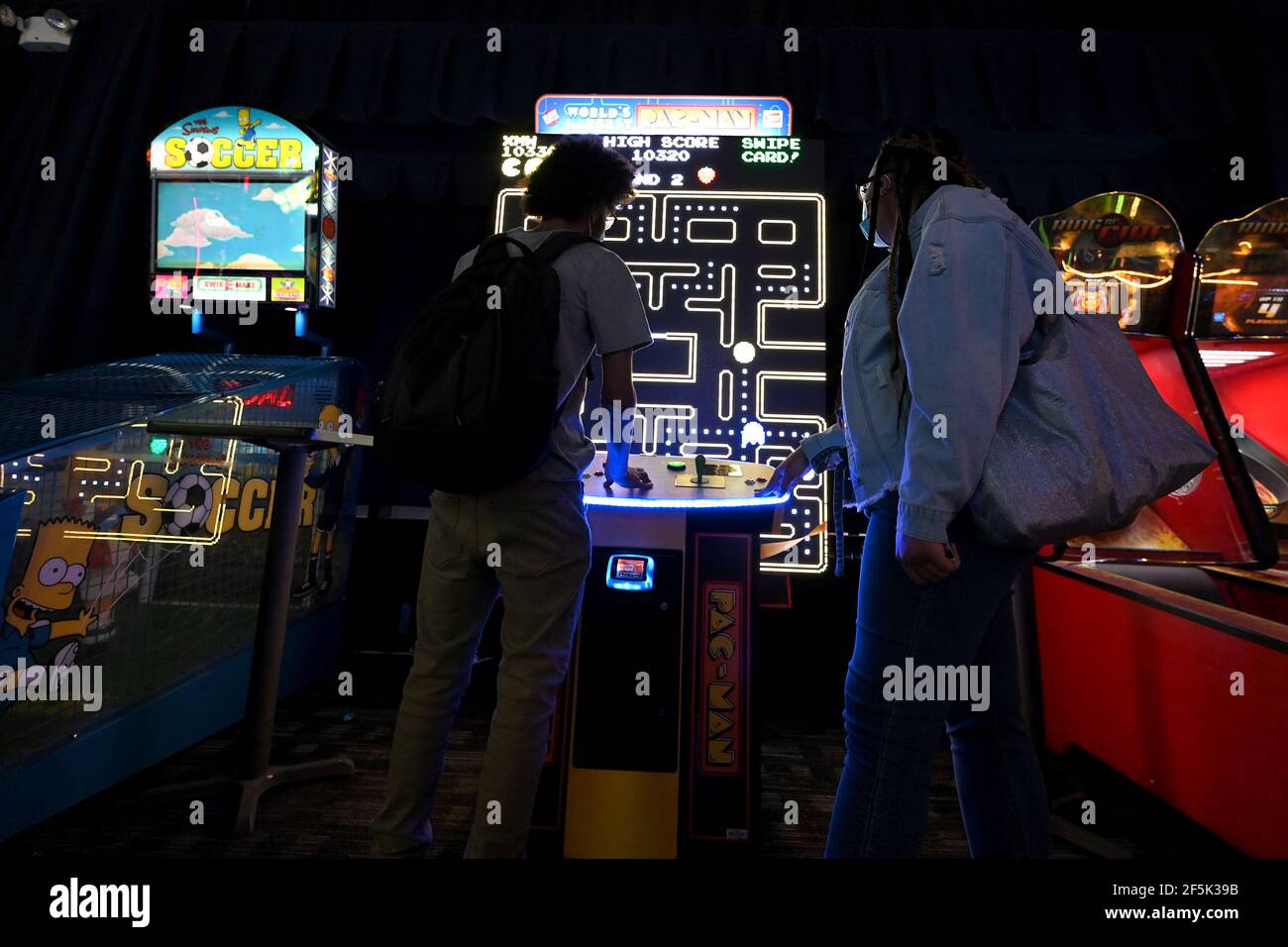 People playing an arcade Pac-Man game on a large screen inside Dave ...