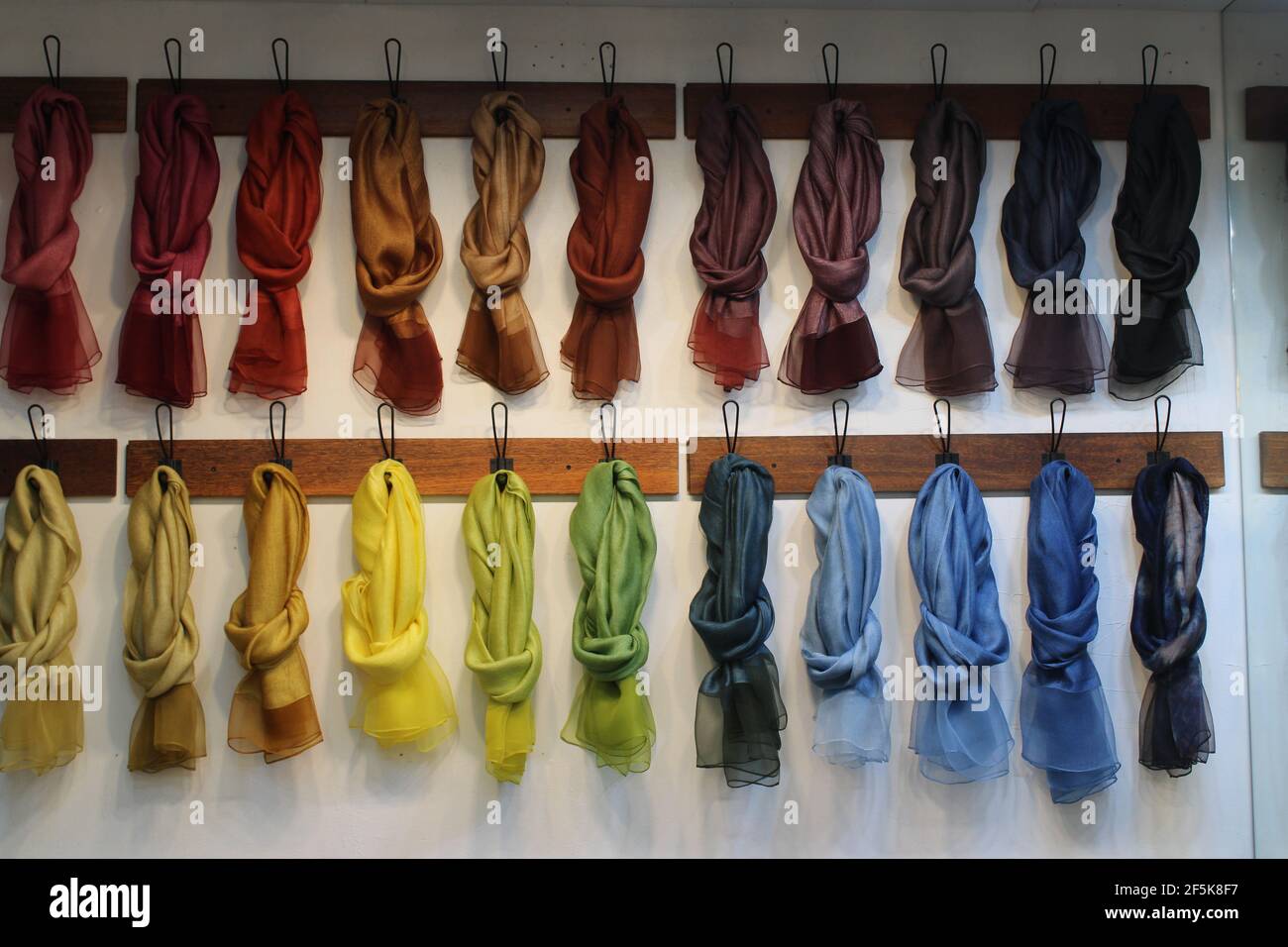 Colorful scarves hanging on a display wall in a clothing store Stock ...