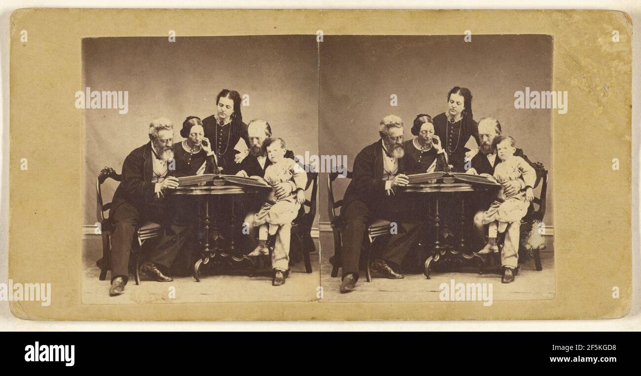 Family of five seated around a table viewing a photographic album ...