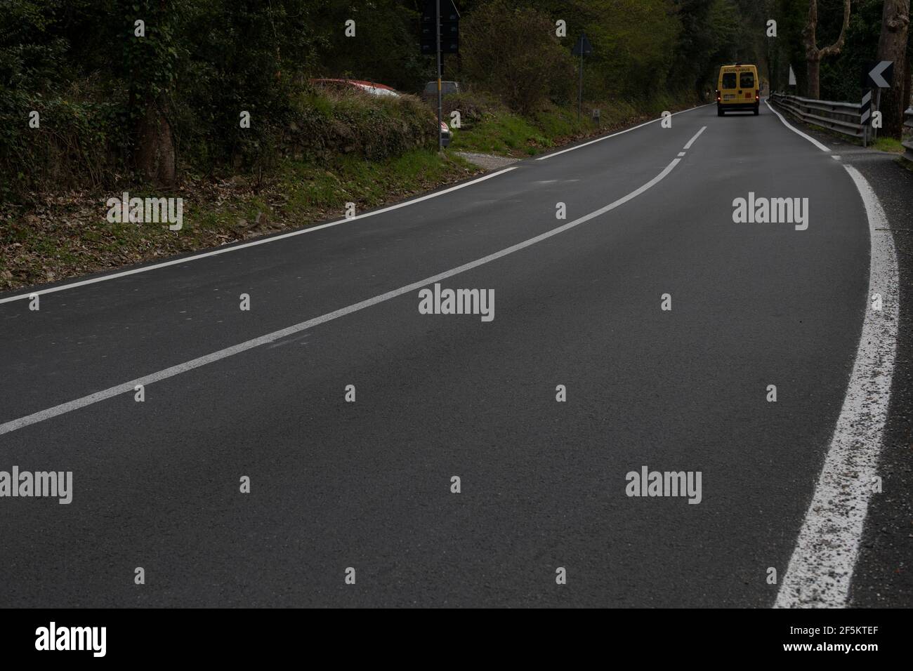 School bus moving away on a two-way asphalted mountain road Stock Photo ...